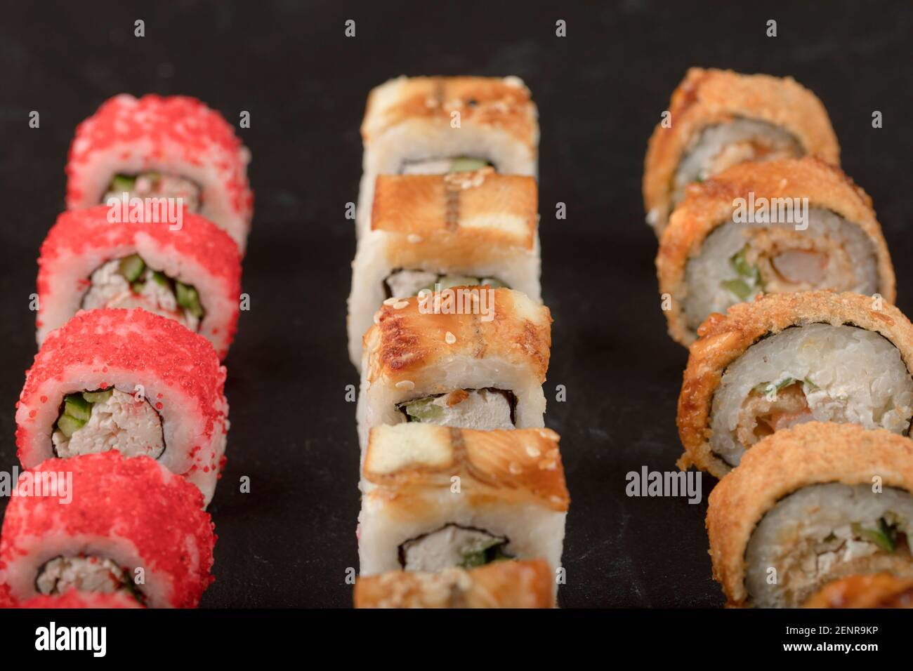 Three different sushi rolls placed on black surface Stock Photo - Alamy