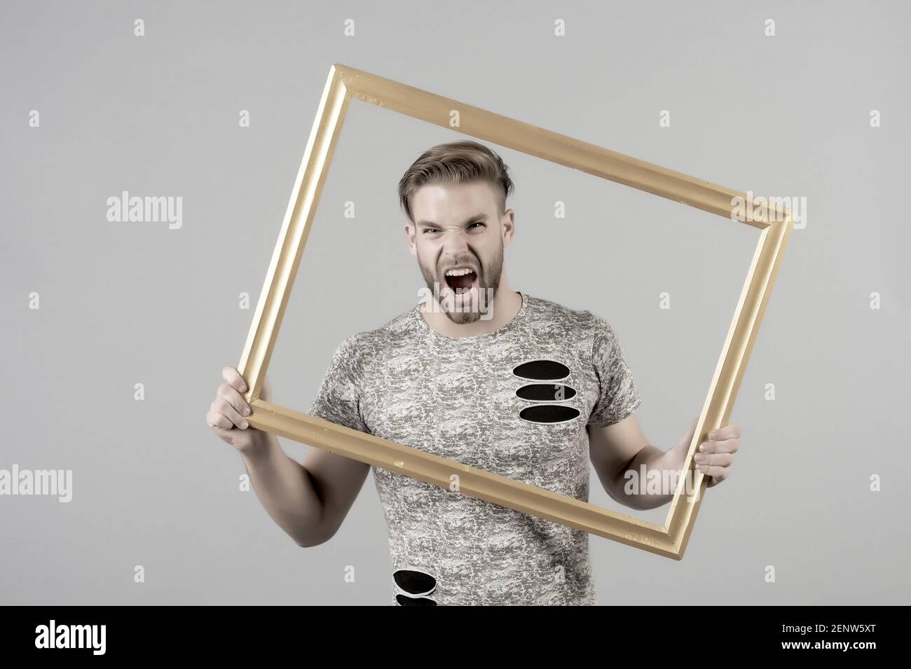 Man shout with picture frame on grey background. Angry macho with beard ...