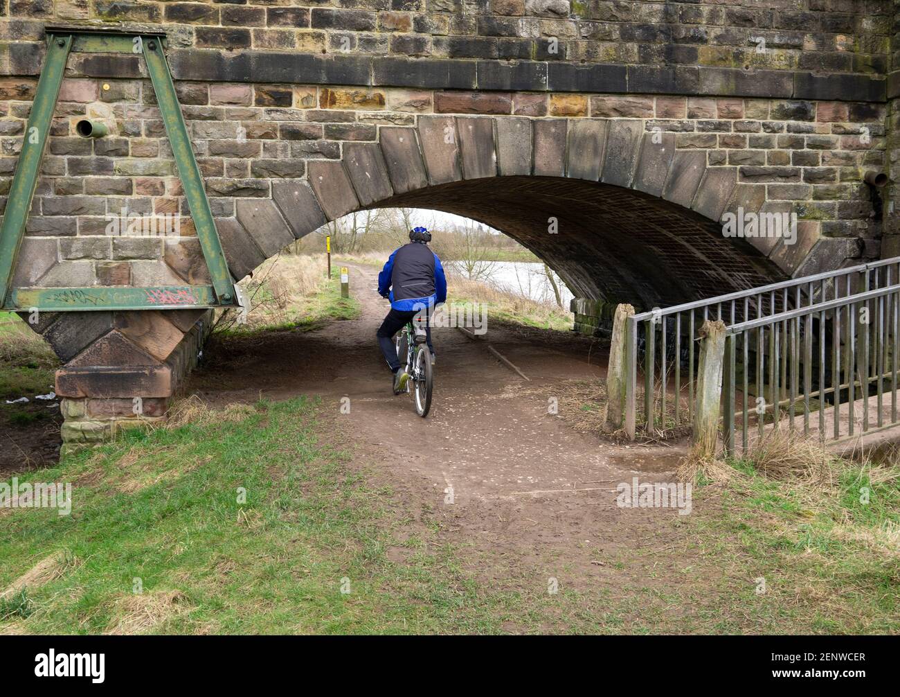 Lone man cycling under a low arch bridge Stock Photo - Alamy