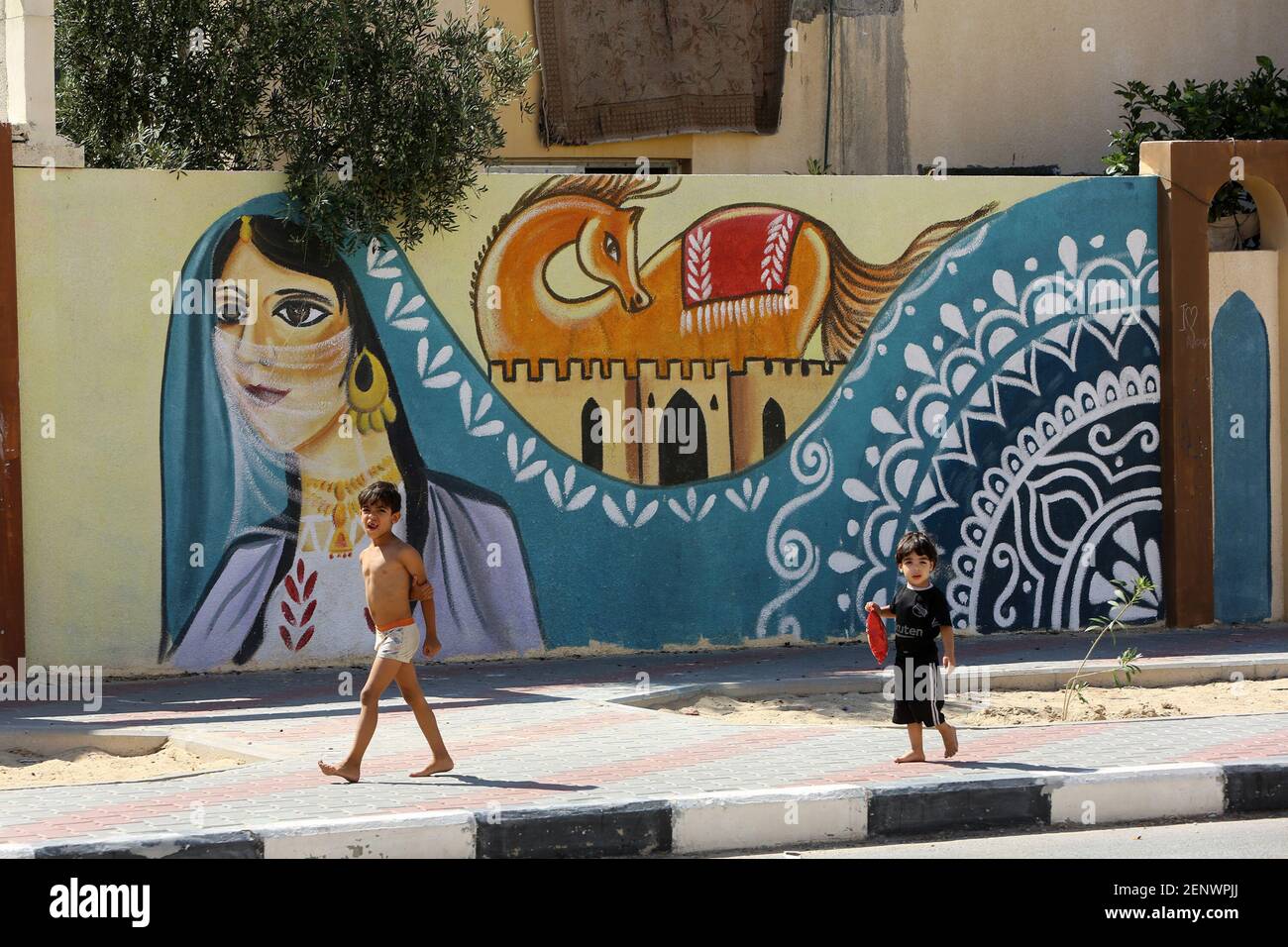 Palestinian children walks next to past a mural along the street in ...