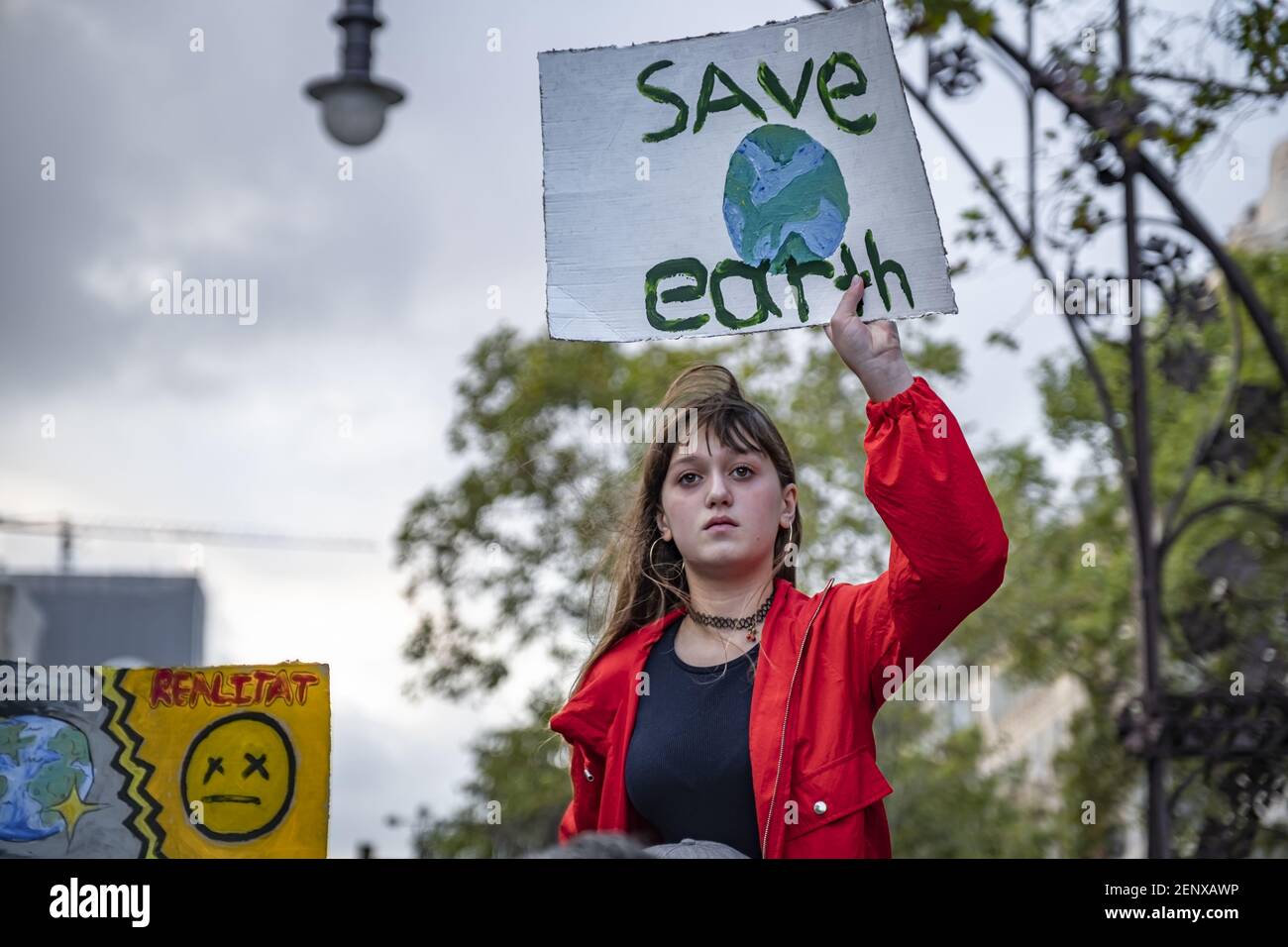 A young protester holds a placard asking to save the planet earth ...