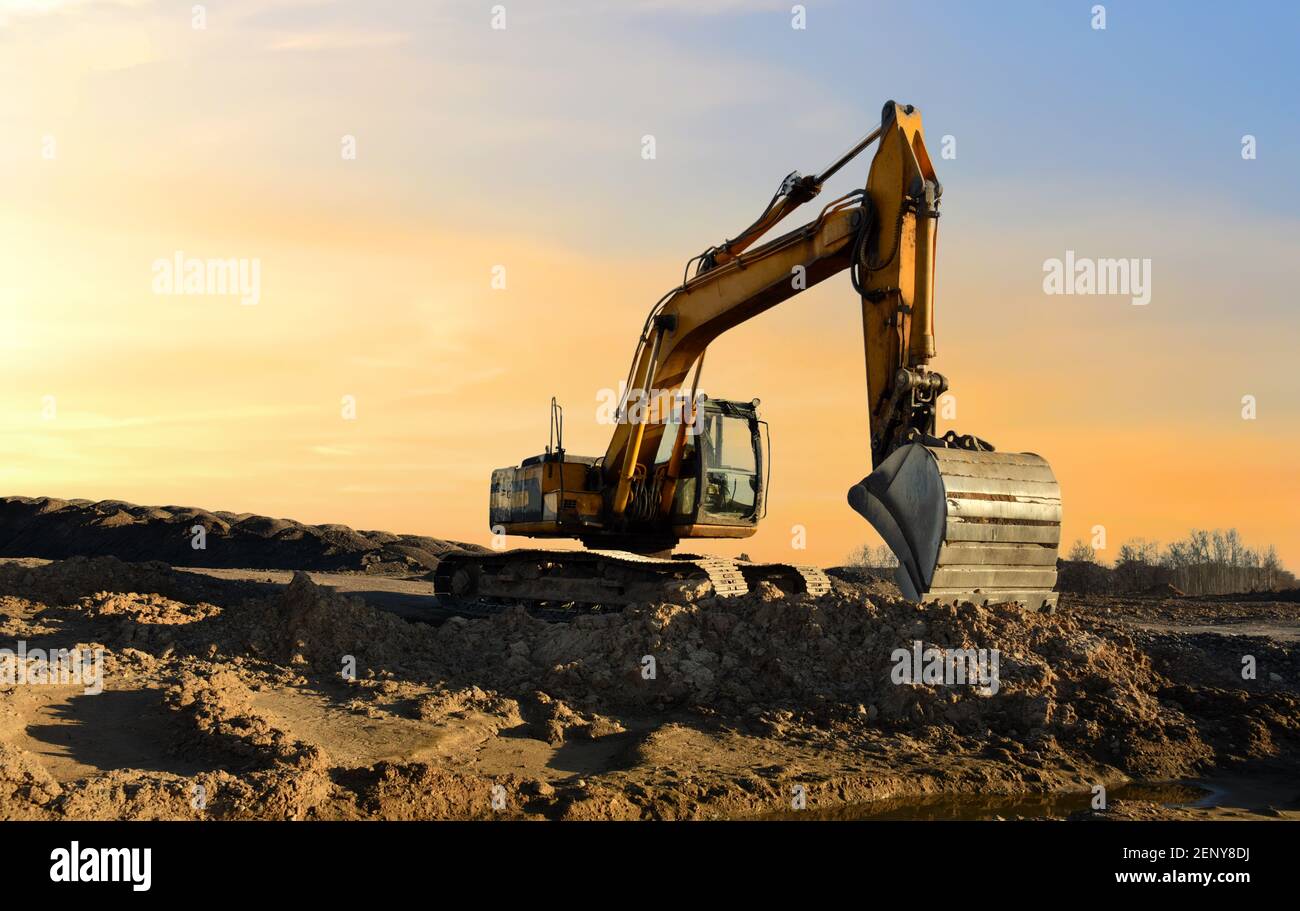 Excavator working on earthmoving at open pit mining on amazing sunset ...