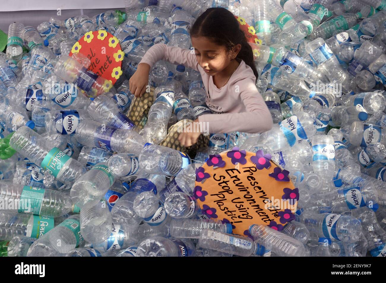 Young girl lay inside heap of plastic used bottles during International ...