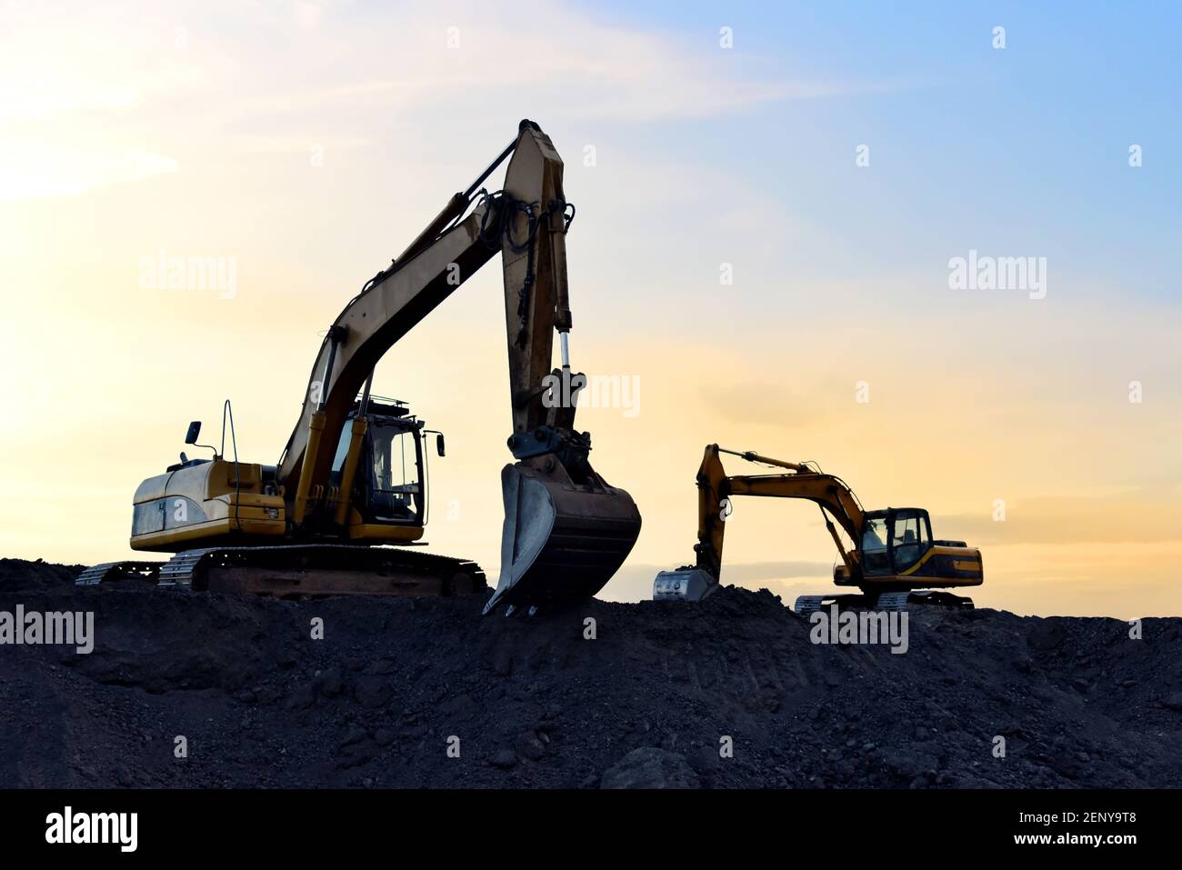 Excavator working on earthmoving at open pit mining on sunset ...