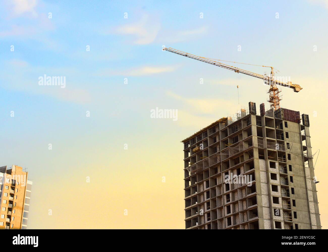 Tower crane in action at construction site on blue sky background ...