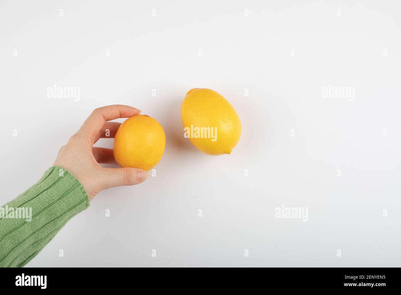 Female hand holding fresh yellow lemon on white background Stock Photo ...