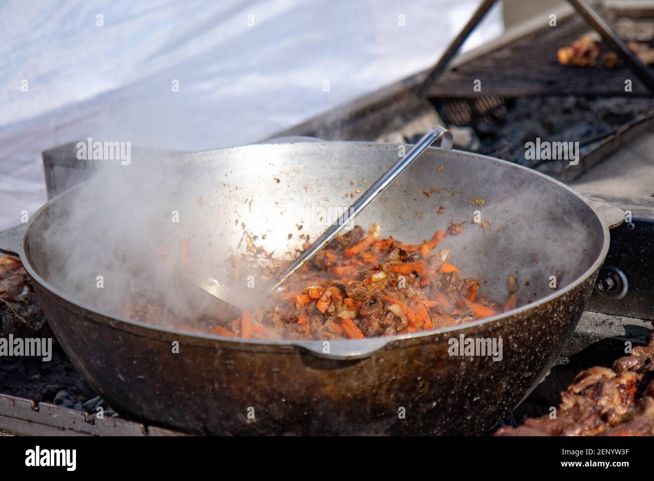 Pilaf prepare in a cauldron on a fire. Roasted carrots and meat. As a ...
