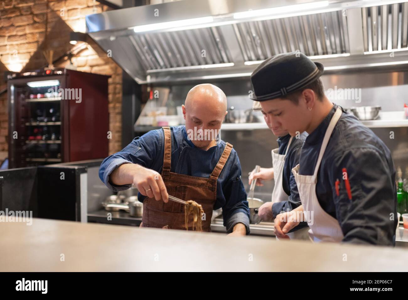 Team of male cooks serving yummy pasta while working in cafeteria ...