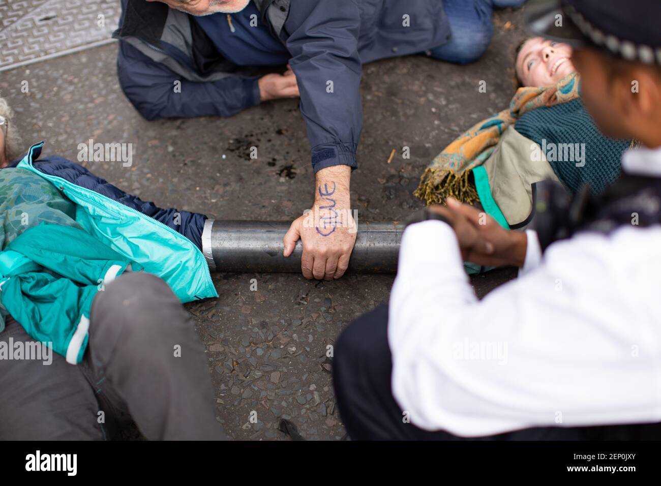 A policeman looks onto protesters who glued themselves to the road ...