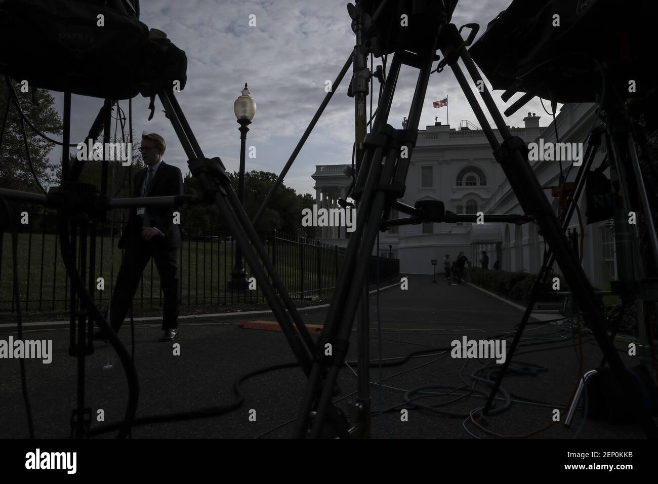 A person walks on the North Lawn of the White House as TV cameras are ...