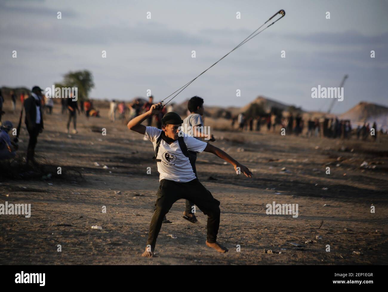 A Palestinian demonstrator uses a slingshot to throw stones during an ...