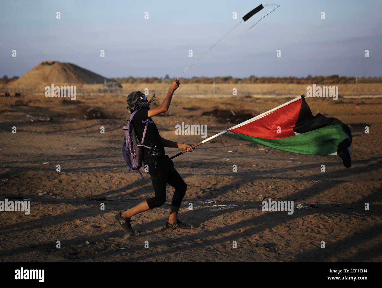 A Palestinian demonstrator uses a slingshot to throw stones during an ...