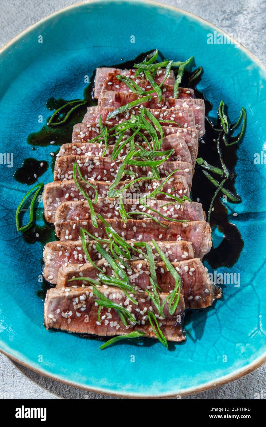 Beef tataki with sauce and sesame on blue plate. Japanese food Stock ...
