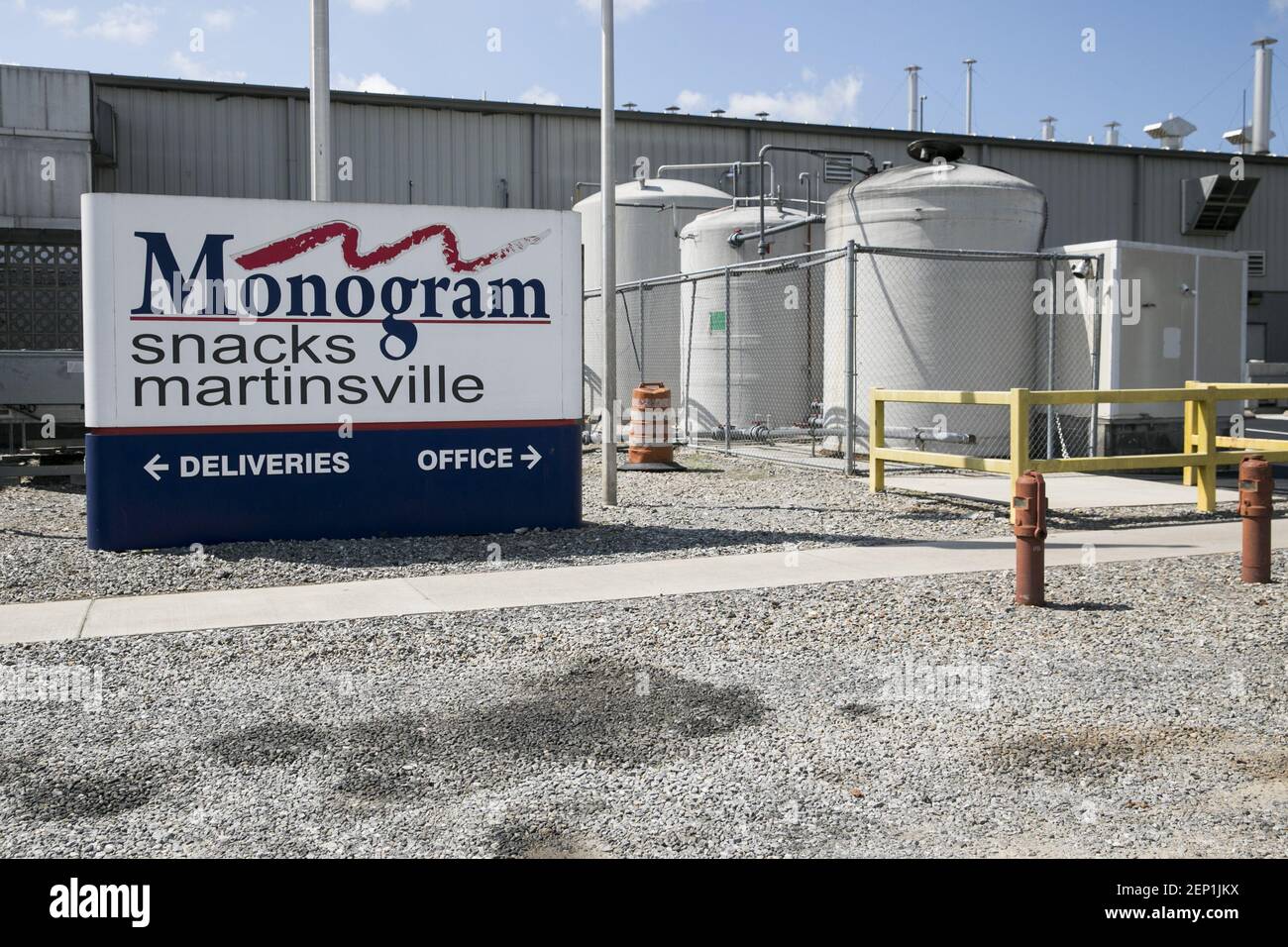 A logo sign outside of a facility occupied by Monogram Snacks, a ...