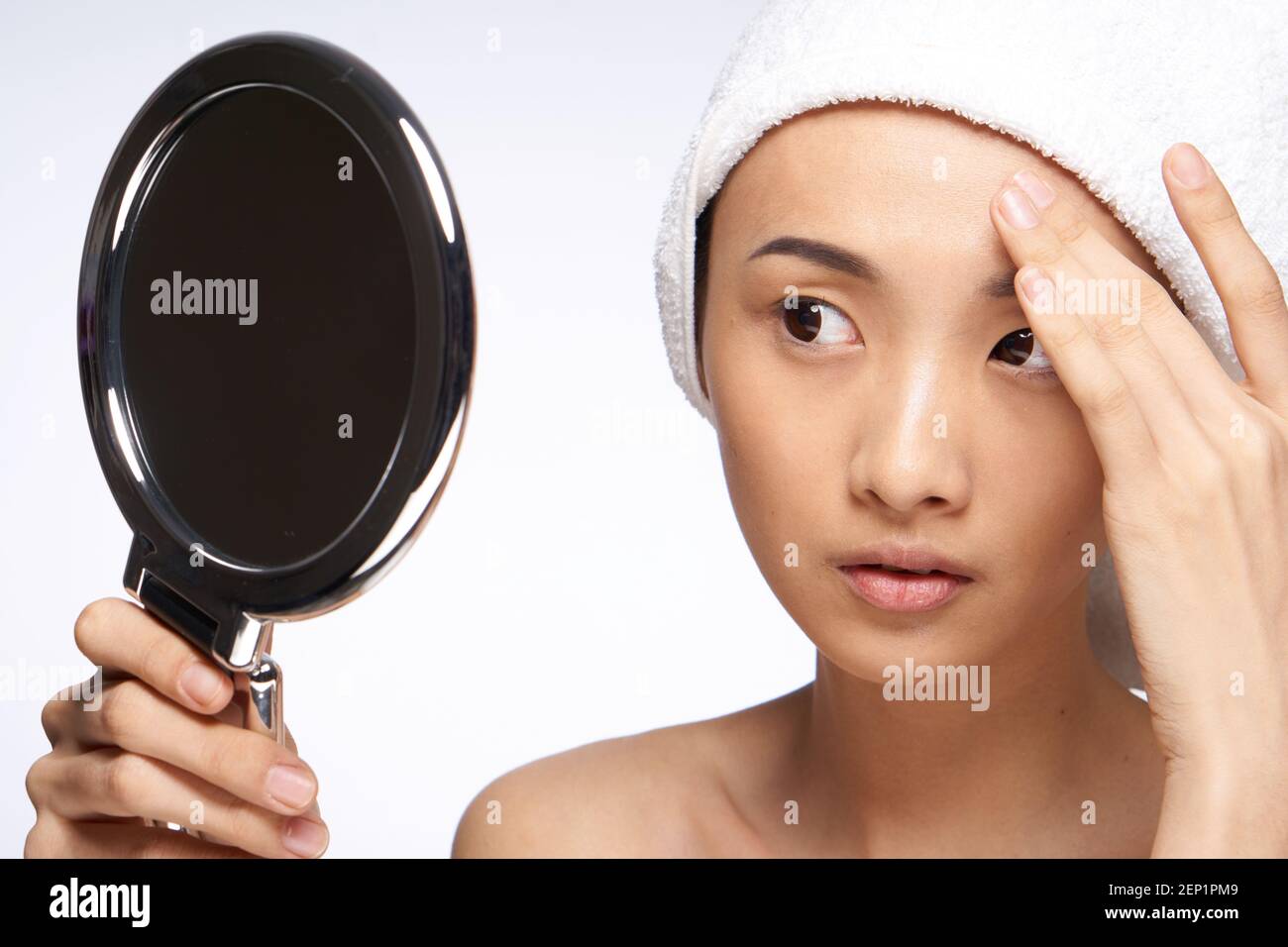 Woman Of Asian Appearance Touches Her Face With Her Hand And Looks In