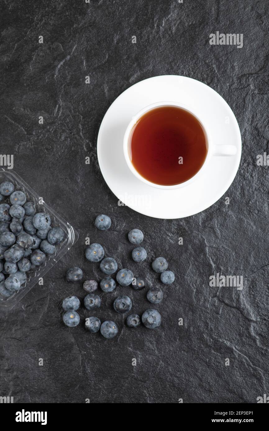 Plastic package of delicious fresh blueberries with cup of hot tea ...