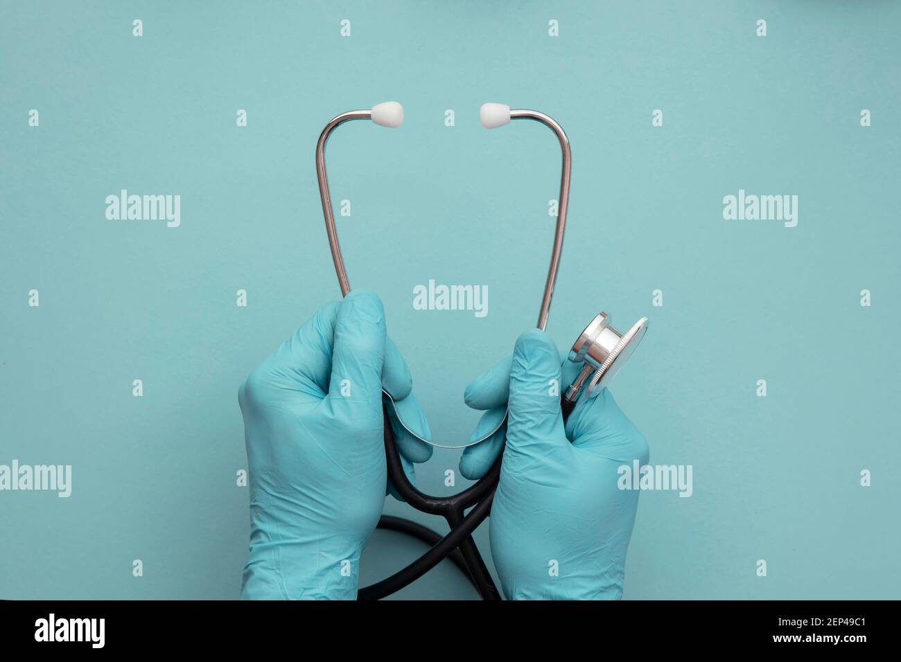 A doctor wearing blue surgical gloves holding a medical stethoscope ...