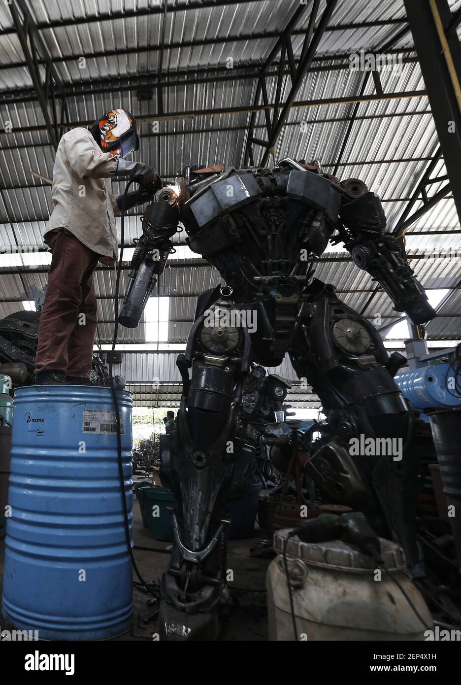 A metalworker seen welding a statue of Transformers at Ban Hun Lek, a ...