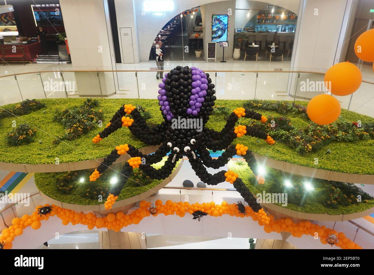 A giant spider made of balloons is put in the lobby of a shopping mall ...