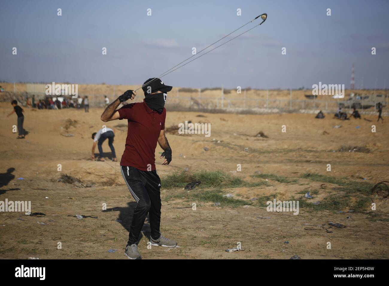 A Palestinian demonstrator uses a slingshot to throw stones during an ...