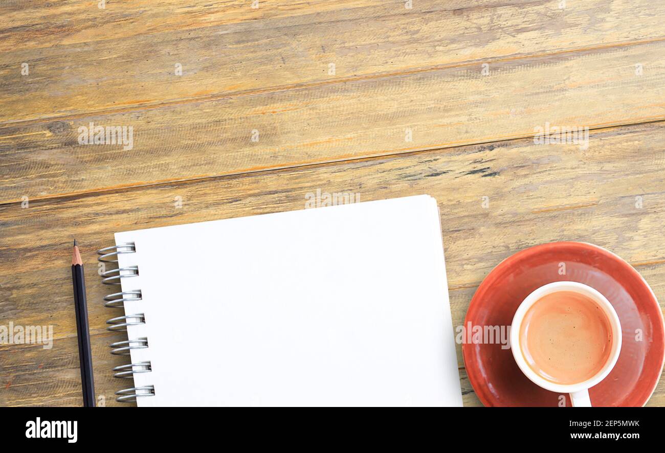 Notepad or notebook with pencil and cup of coffee on brown wood table ...