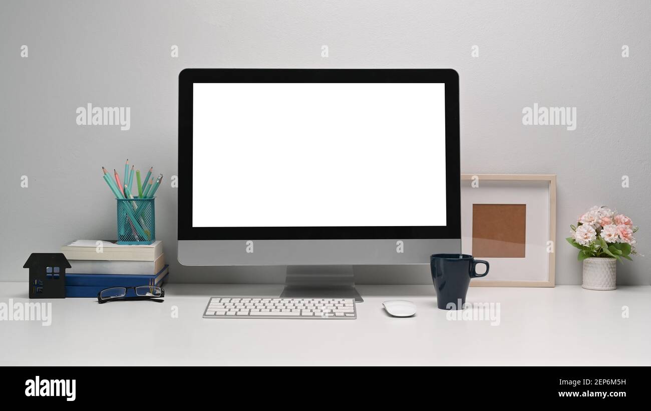 Front view of modern computer with blank screen and office supplies on ...