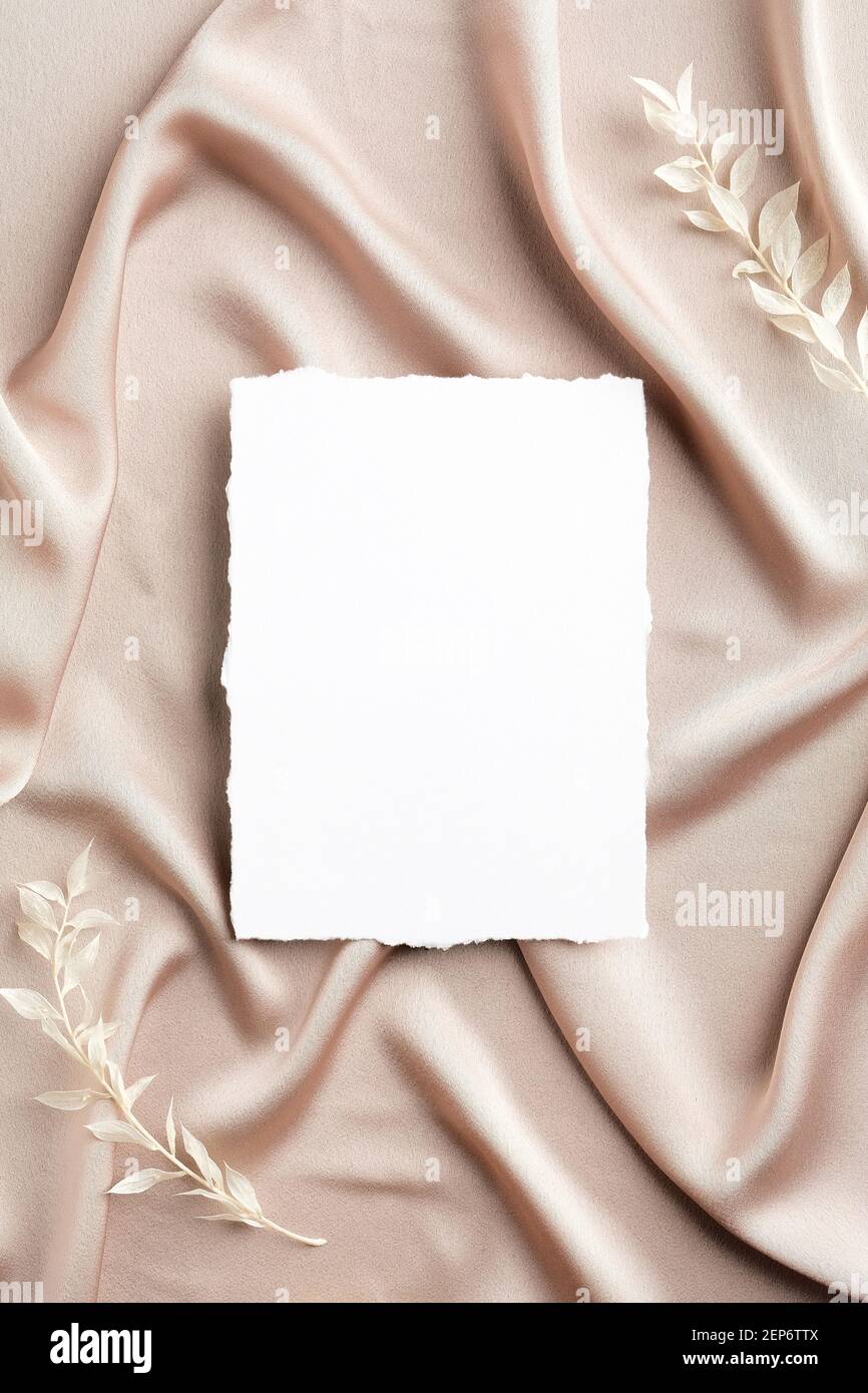 Blank white paper card on satin fabric with dried flowers. Flat lay ...