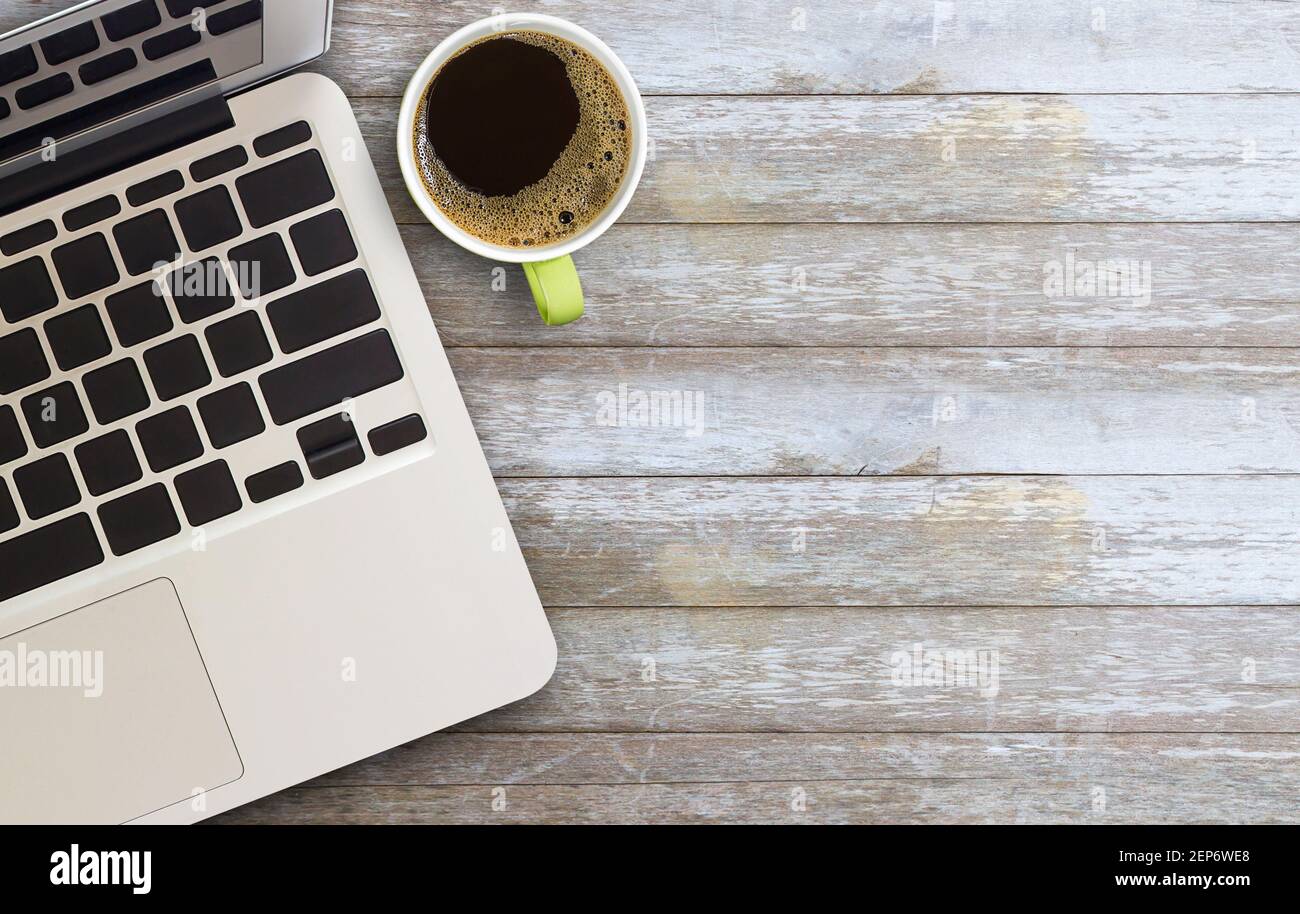 Top view of laptop computer and cup of coffee on brown wood table ...