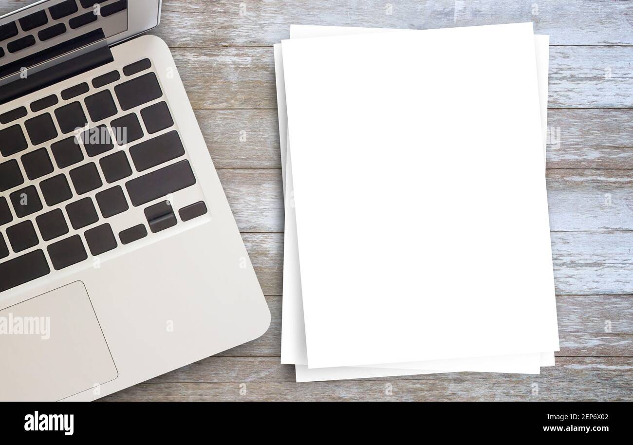Top view of laptop computer and white paper on brown wood table ...