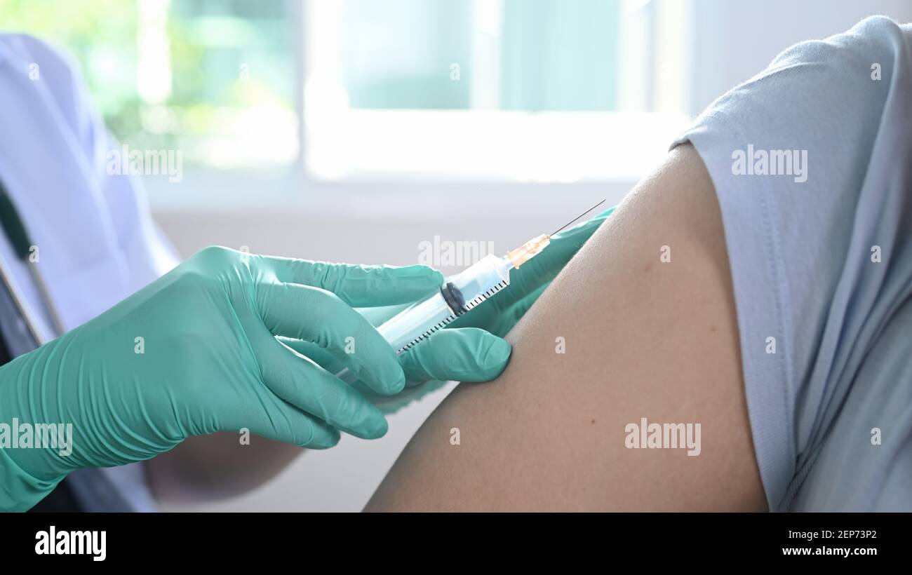 Close up view of doctor holding syringe and giving injection to patient ...