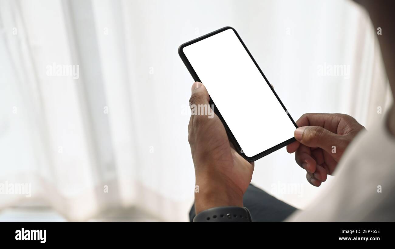 Close up man holding mobile phone with white screen while sitting on ...