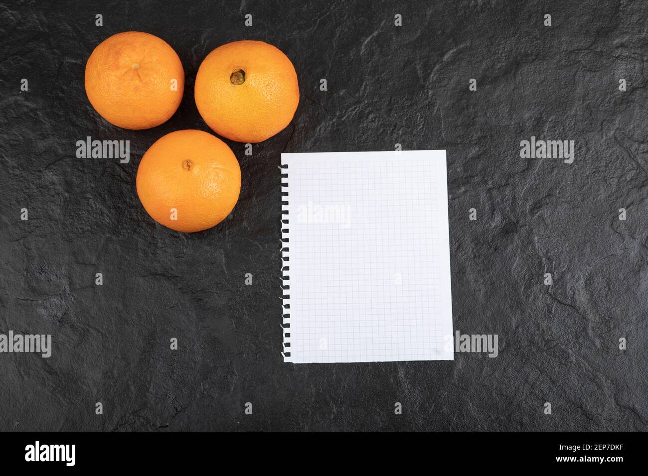 Healthy orange fruits with an empty sheet of paper on black table Stock ...