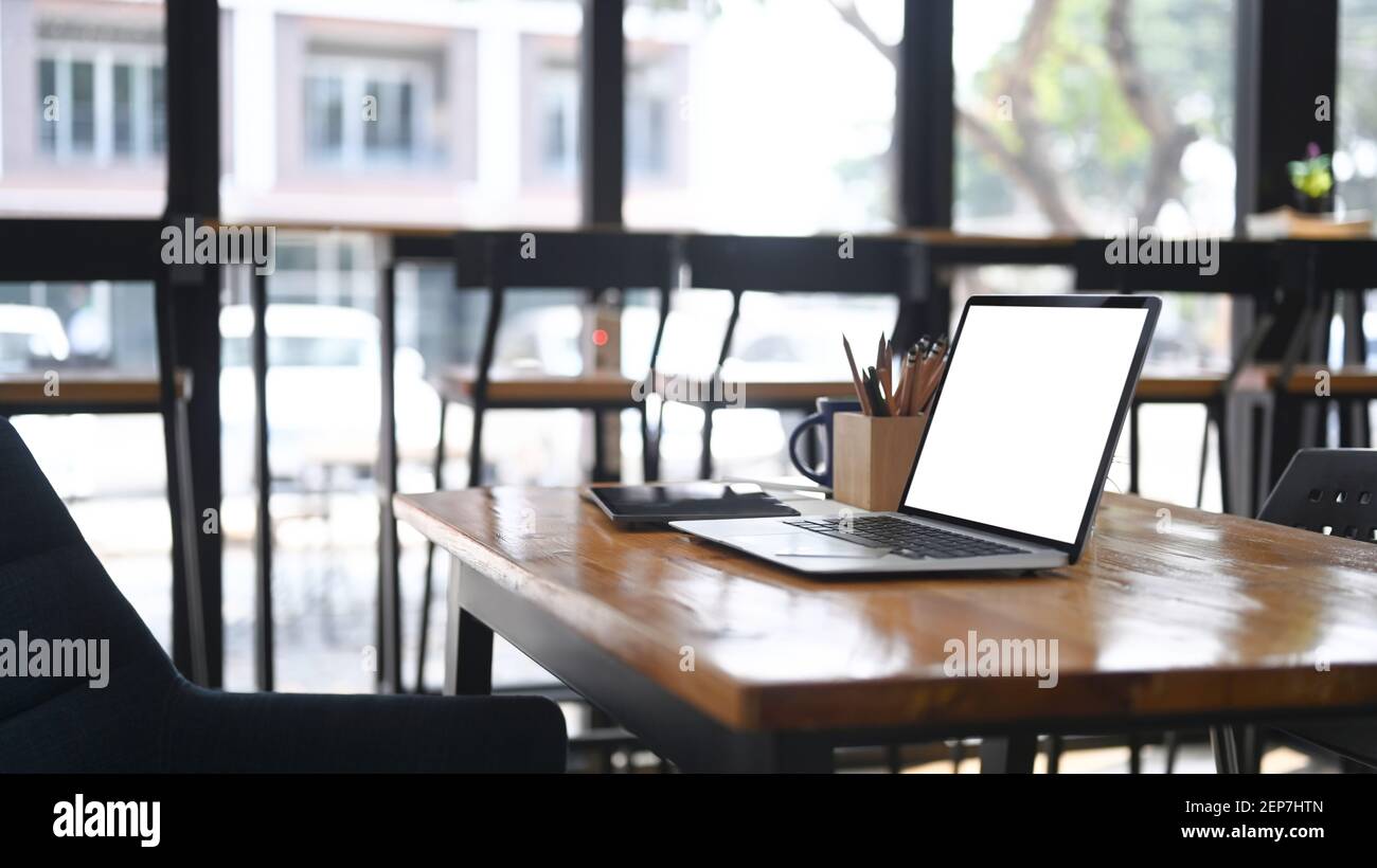Side view of computer laptop with empty screen and digital tablet on ...