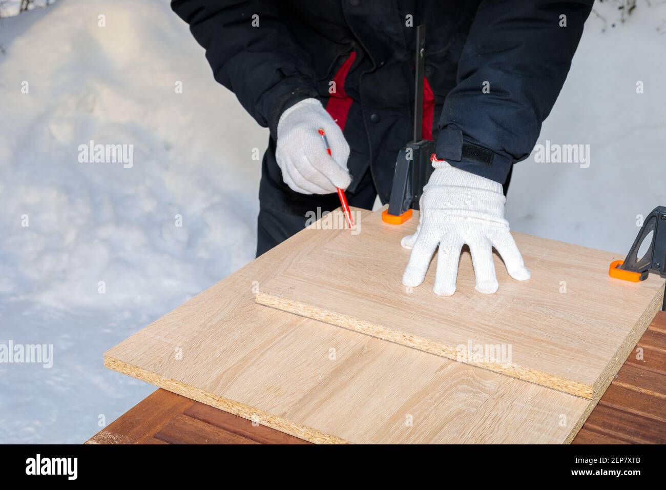 A man, a worker, marks it with a square and a pencil on a chipboard ...
