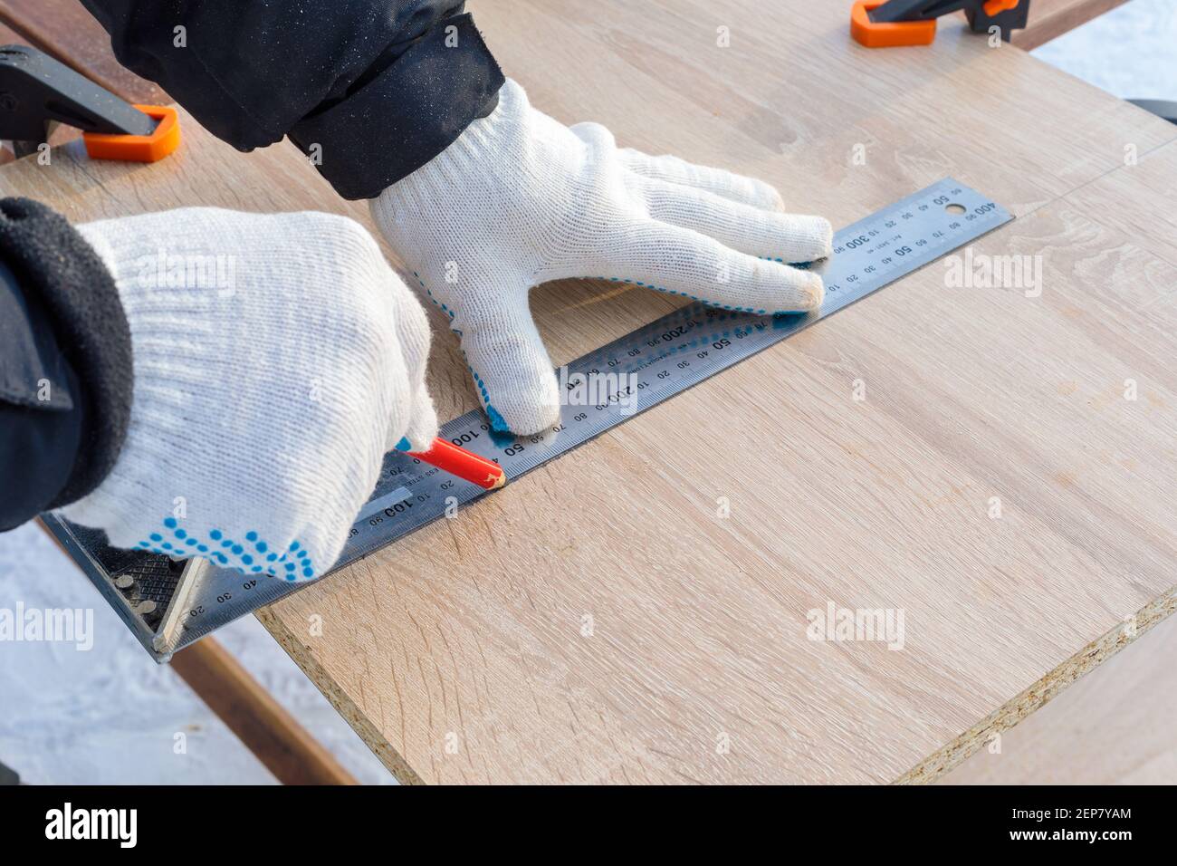 A man, a worker, marks it with a square and a pencil on a chipboard ...