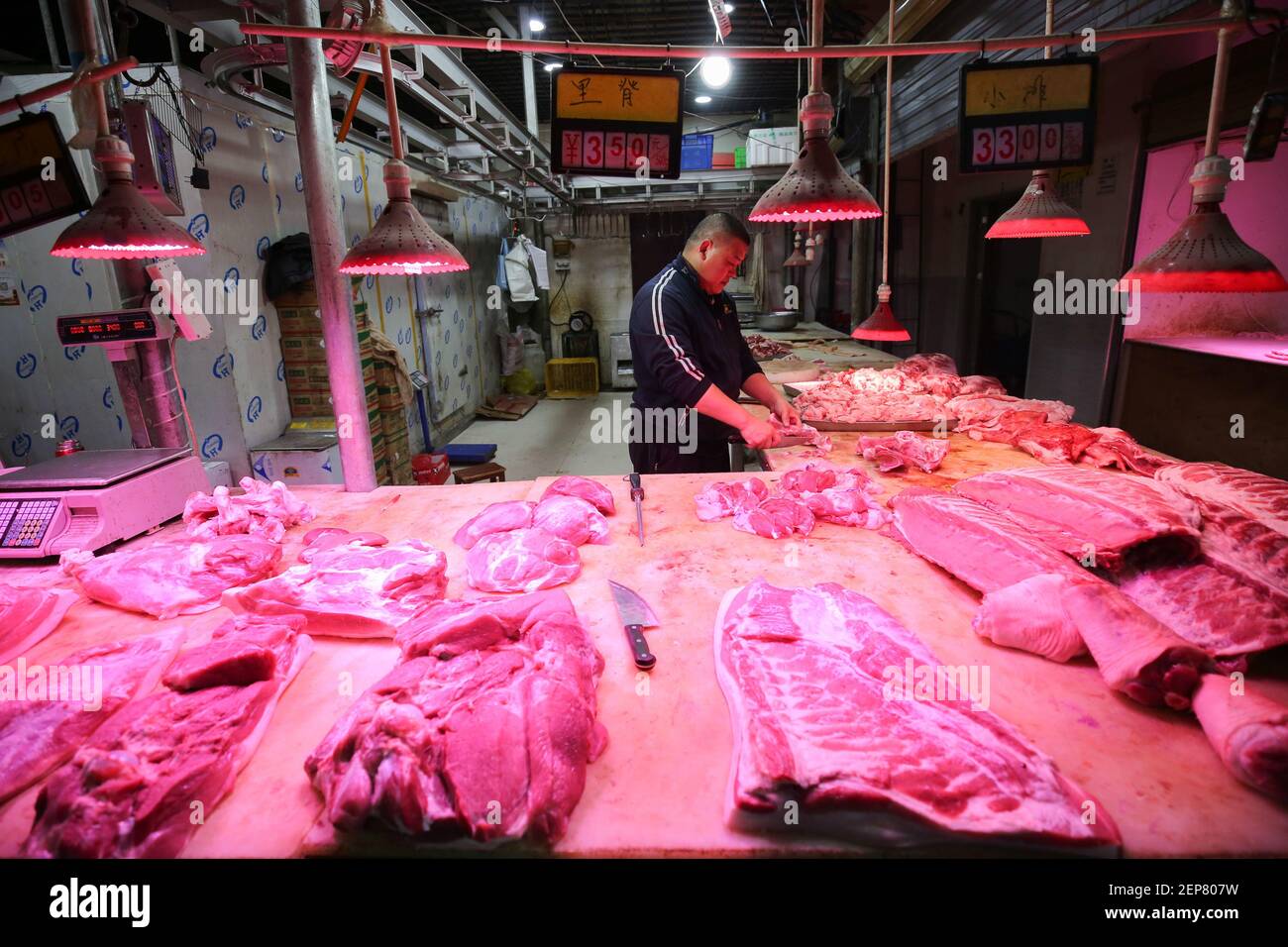 A vendor sections pork at the meat stall in a market in Xi'an city ...