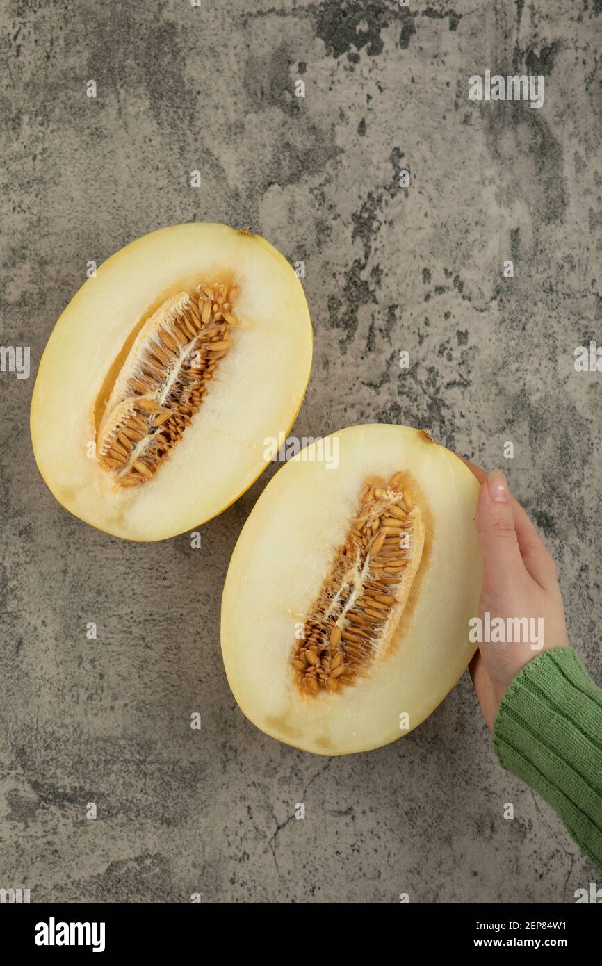 Female hand touching halved sweet melons on marble surface Stock Photo ...