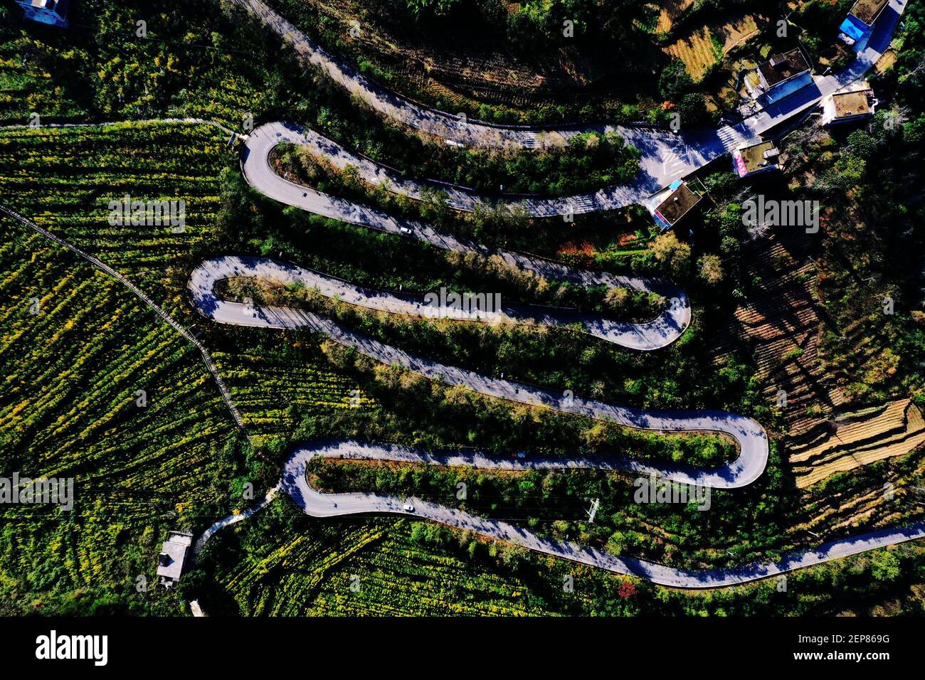 An aerial view of a zigzag highway connecting remote and poor villages locating among mountains ...