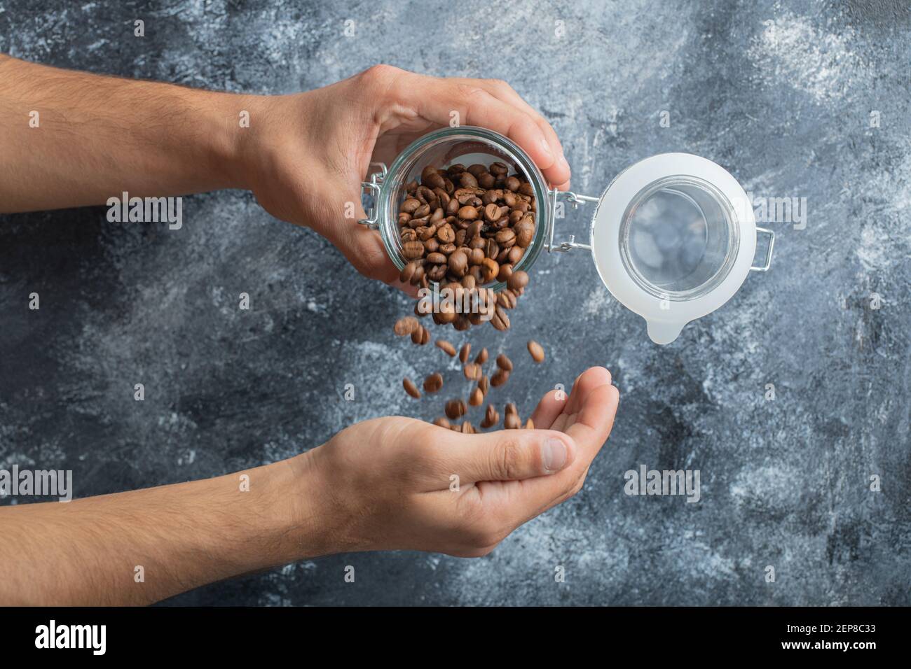 Male hand holding glass jar of aromatic coffee beans on marble ...