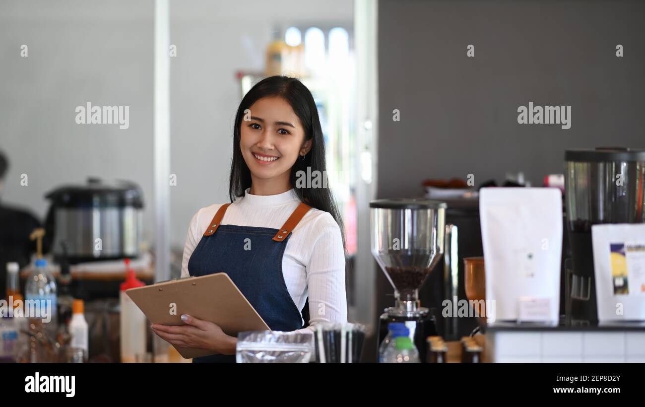 Successful small business owner smiling and standing behind the counter ...