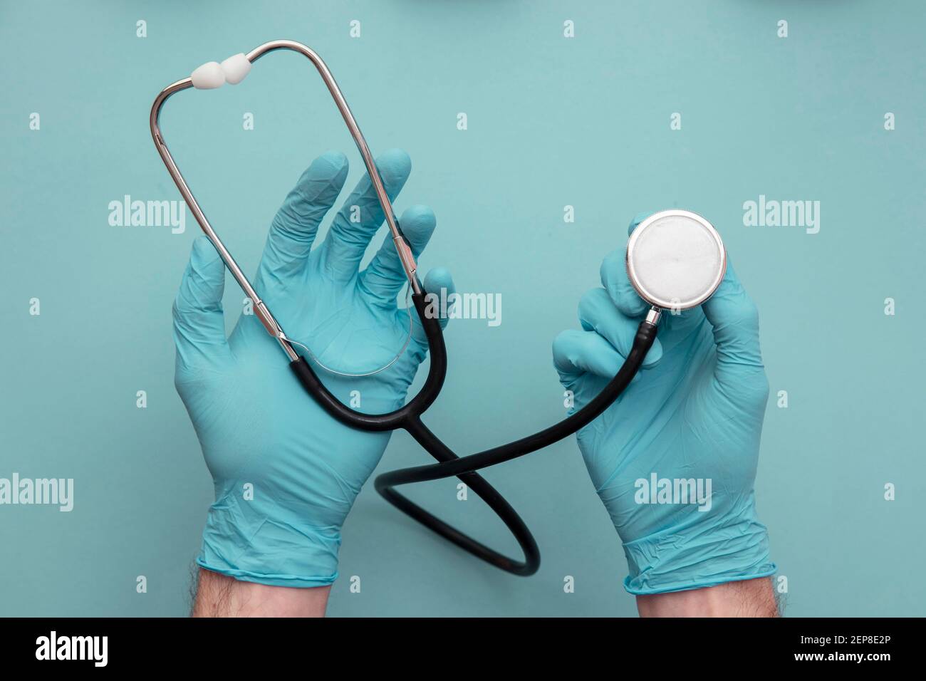 A doctor wearing blue surgical gloves holding a medical stethoscope ...