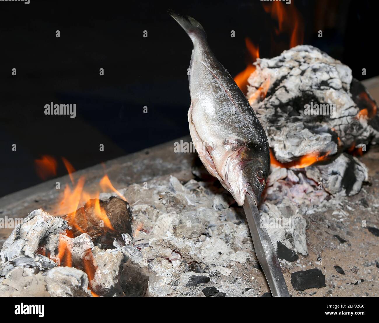 Cooking fish grilled over hot coals bonfire Stock Photo - Alamy