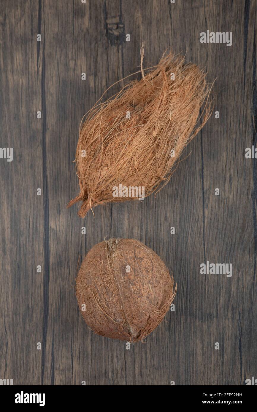 Two hairy hard coconut on wooden surface Stock Photo - Alamy