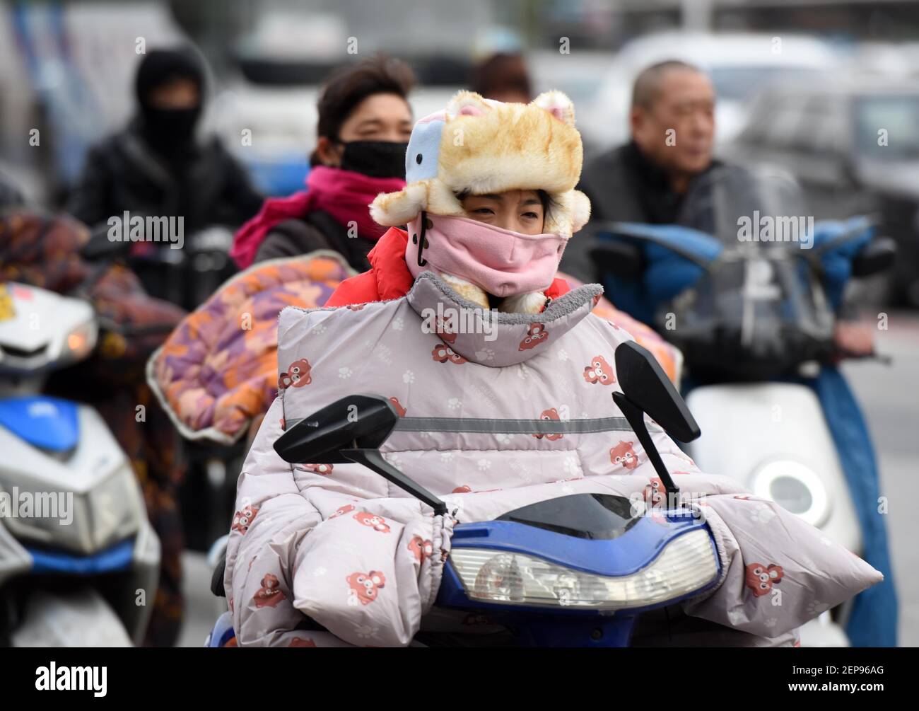 Local Chinese residents wearing heavy clothing commute by electric bike ...