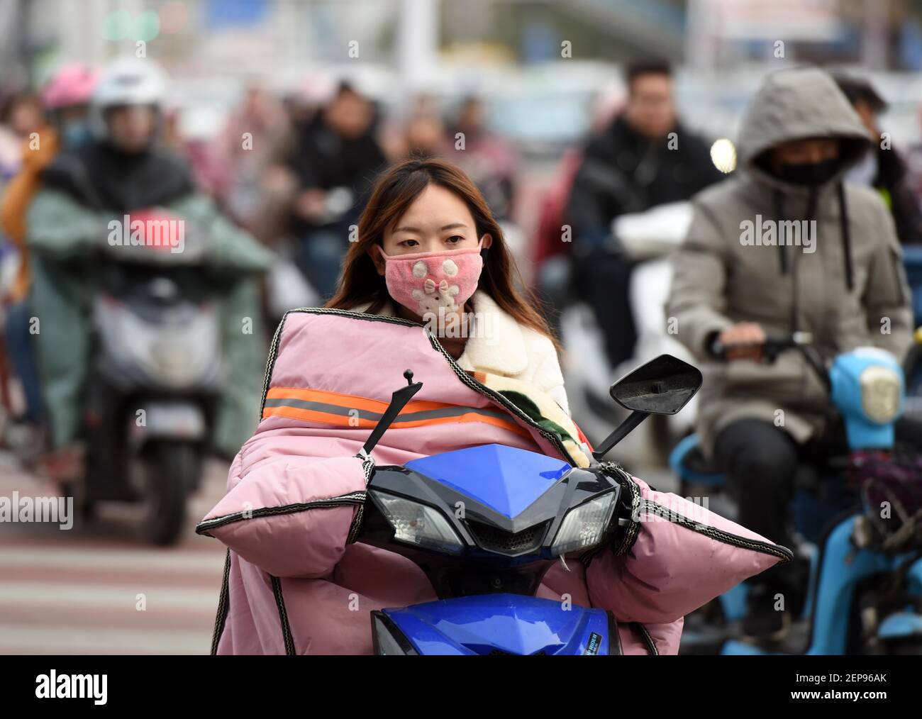 Local Chinese residents wearing heavy clothing commute by electric bike ...