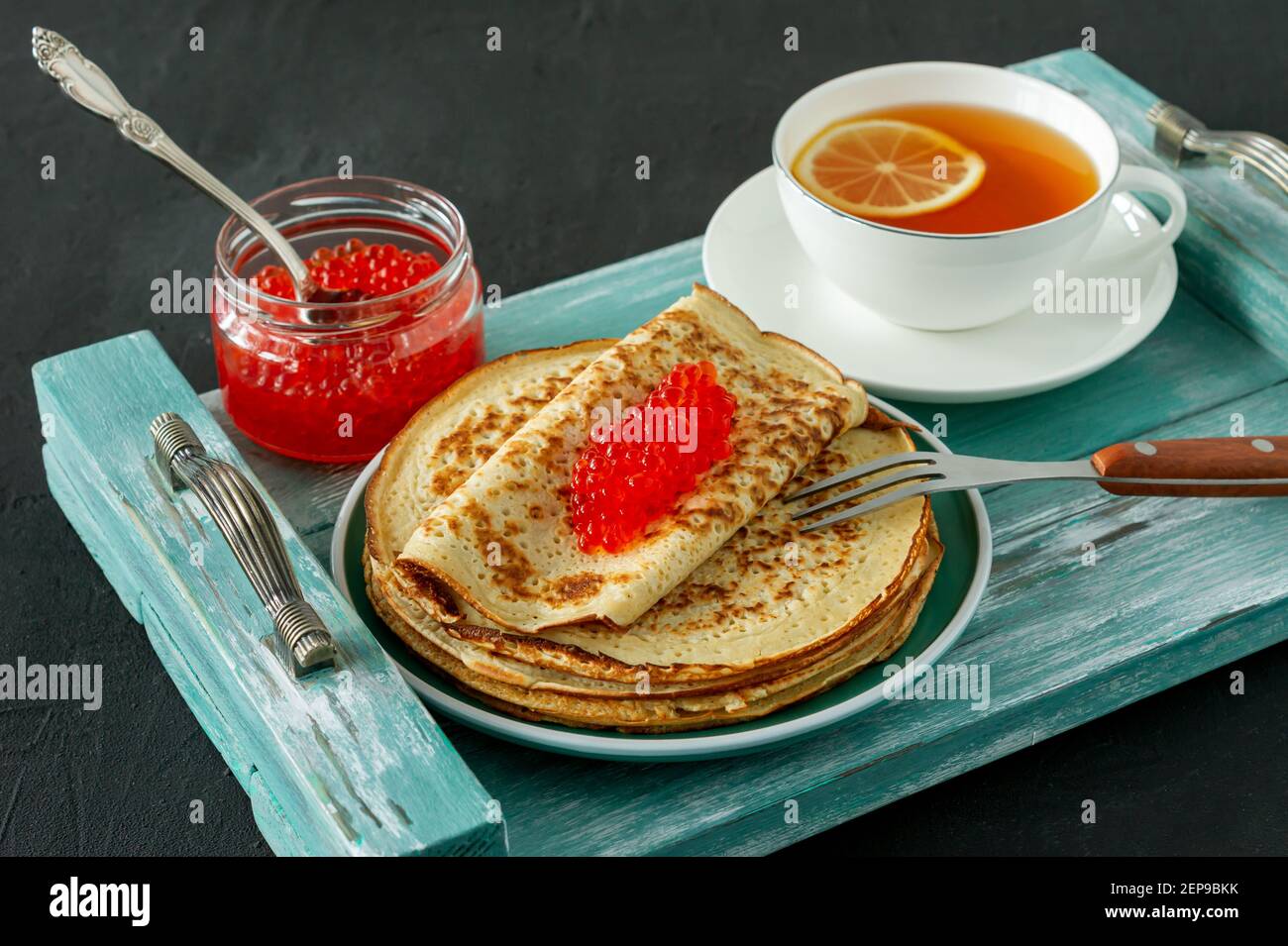 Traditional Russian Crepes Blini stacked in a plate with red caviar and ...