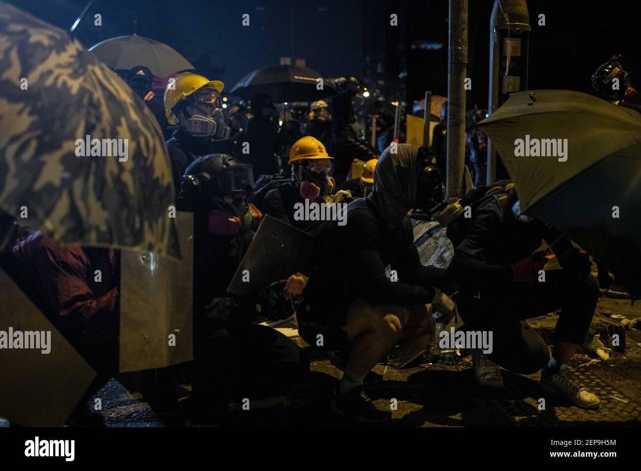 Protesters take cover behind barricades during the clashes with riot ...