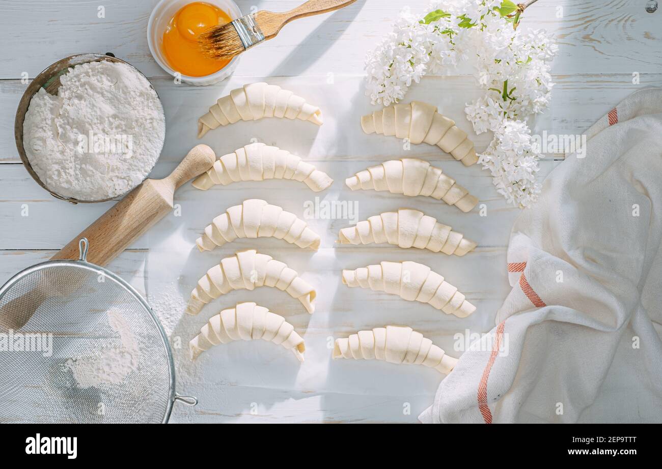 rolled croissant dough and ready for baking on a white wooden table on ...