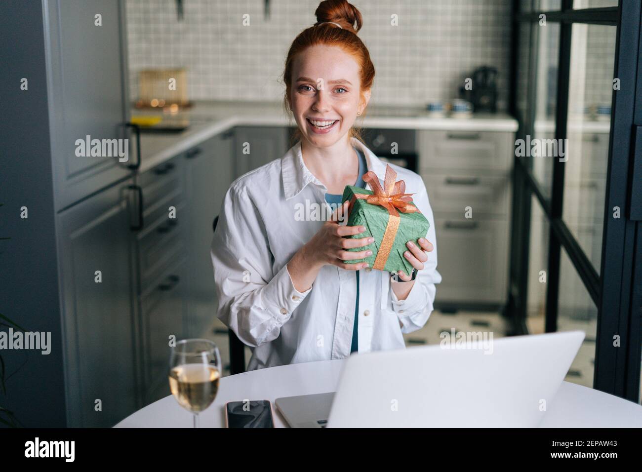 Portrait of satisfied young woman holding present gift box during video ...