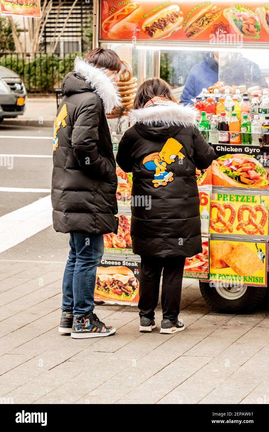 asian couple in identical Simpsons coats at food stands outside of New ...